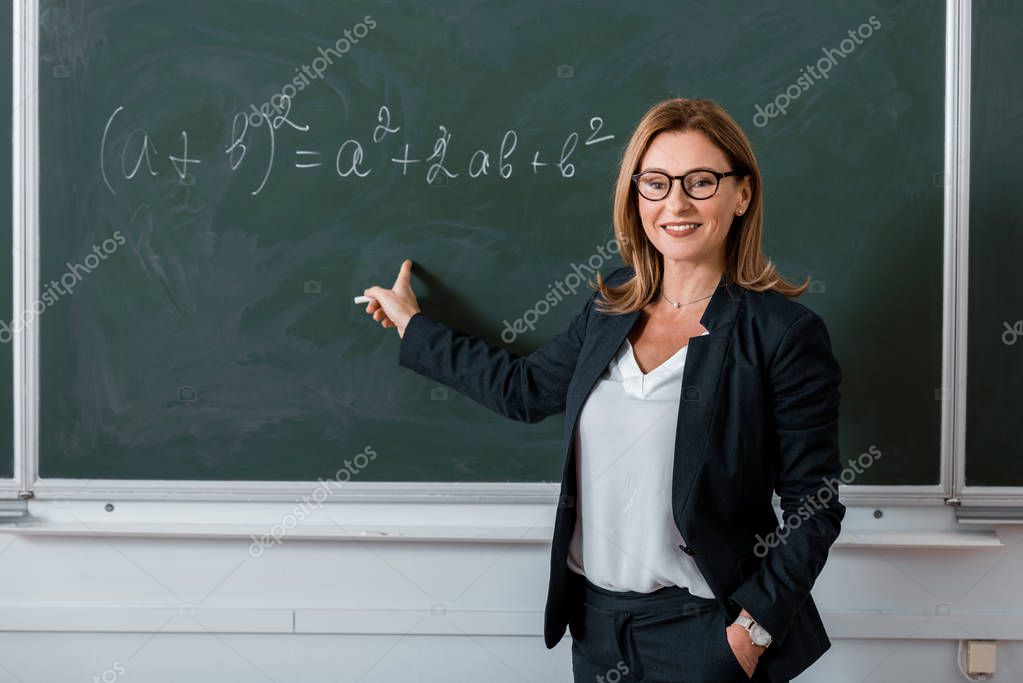 profesora señalando con el dedo la ecuación matemática en pizarra en ...