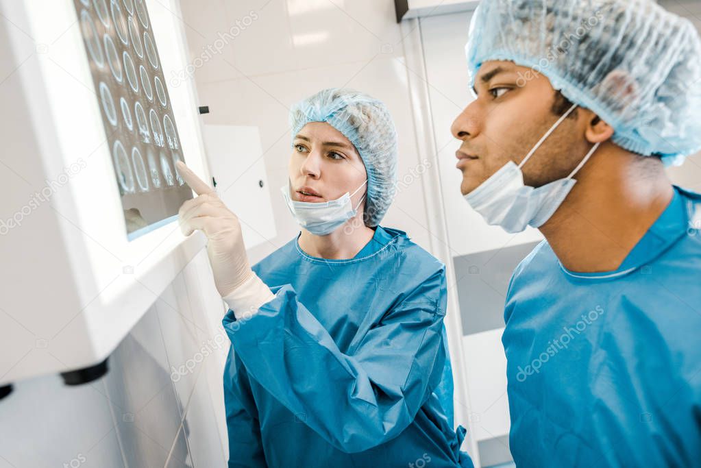 médicos guapos y hermosos en uniformes y máscaras médicas que señalan ...