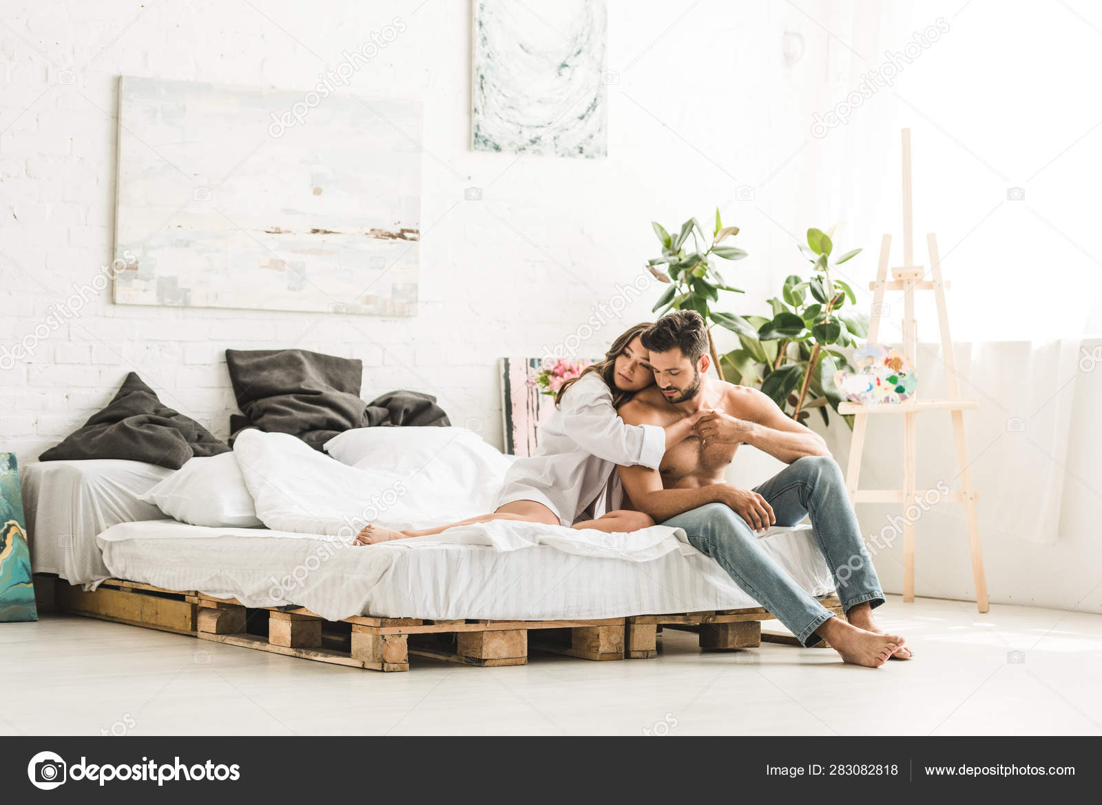 Young Couple Hugging While Sitting Bed Looking Away Stock Photo by ...