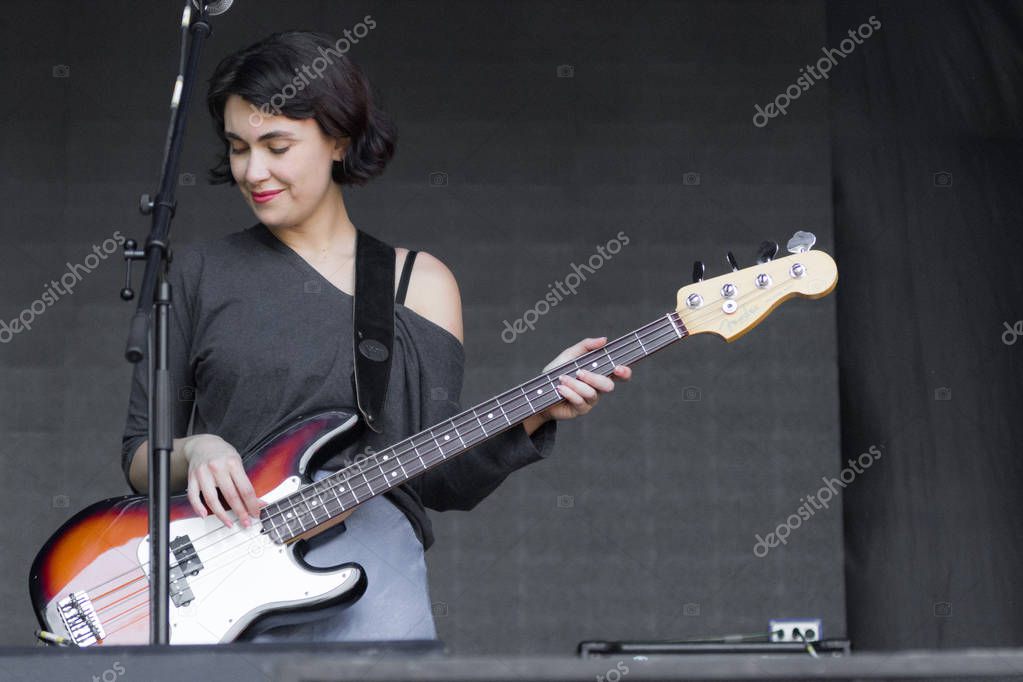 Chica desconocida con bajo eléctrico. Guitarra acústica en manos de una mujer. Instrumento ...