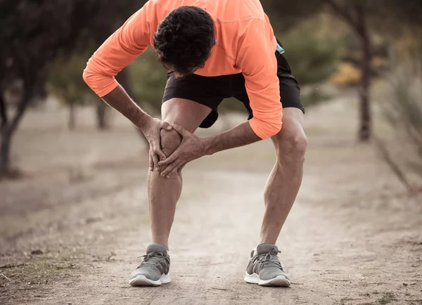 Young fit man holding knee with his hands in pain after suffering ...