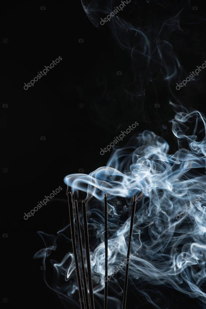 palos de aroma ardiente con humo sobre fondo negro 2024