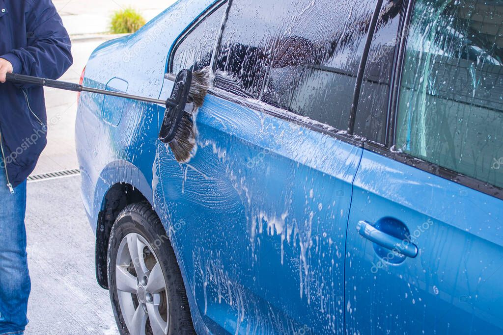 Un hombre lava un coche por su cuenta. Auto-servicio de lavado de autos ...