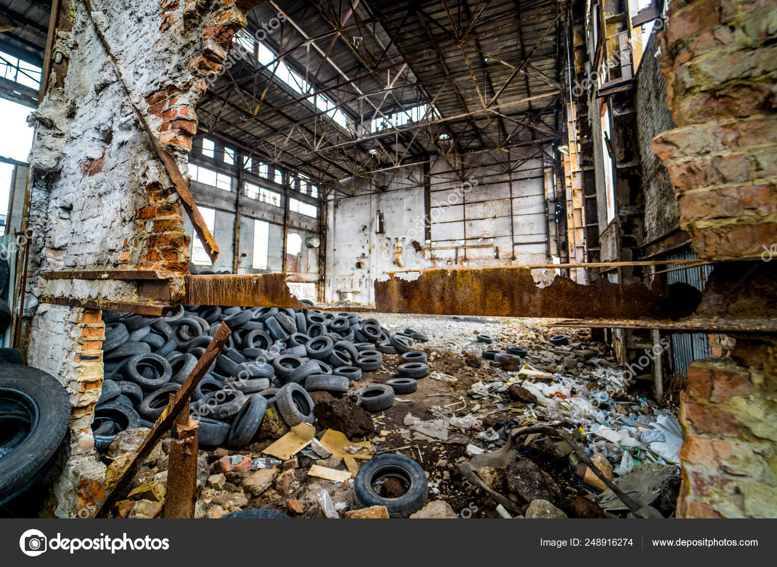Destroyed old factory with garbage and a pile of used rubber tyres ...