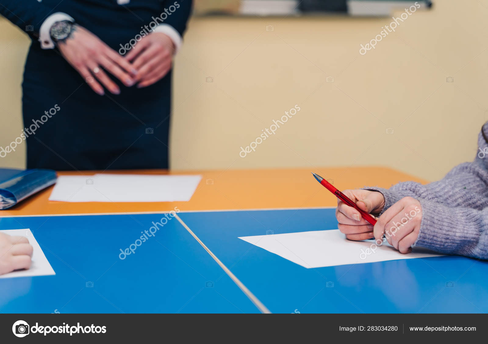 Hand of student is taking exam and writing answer in classroom for ...