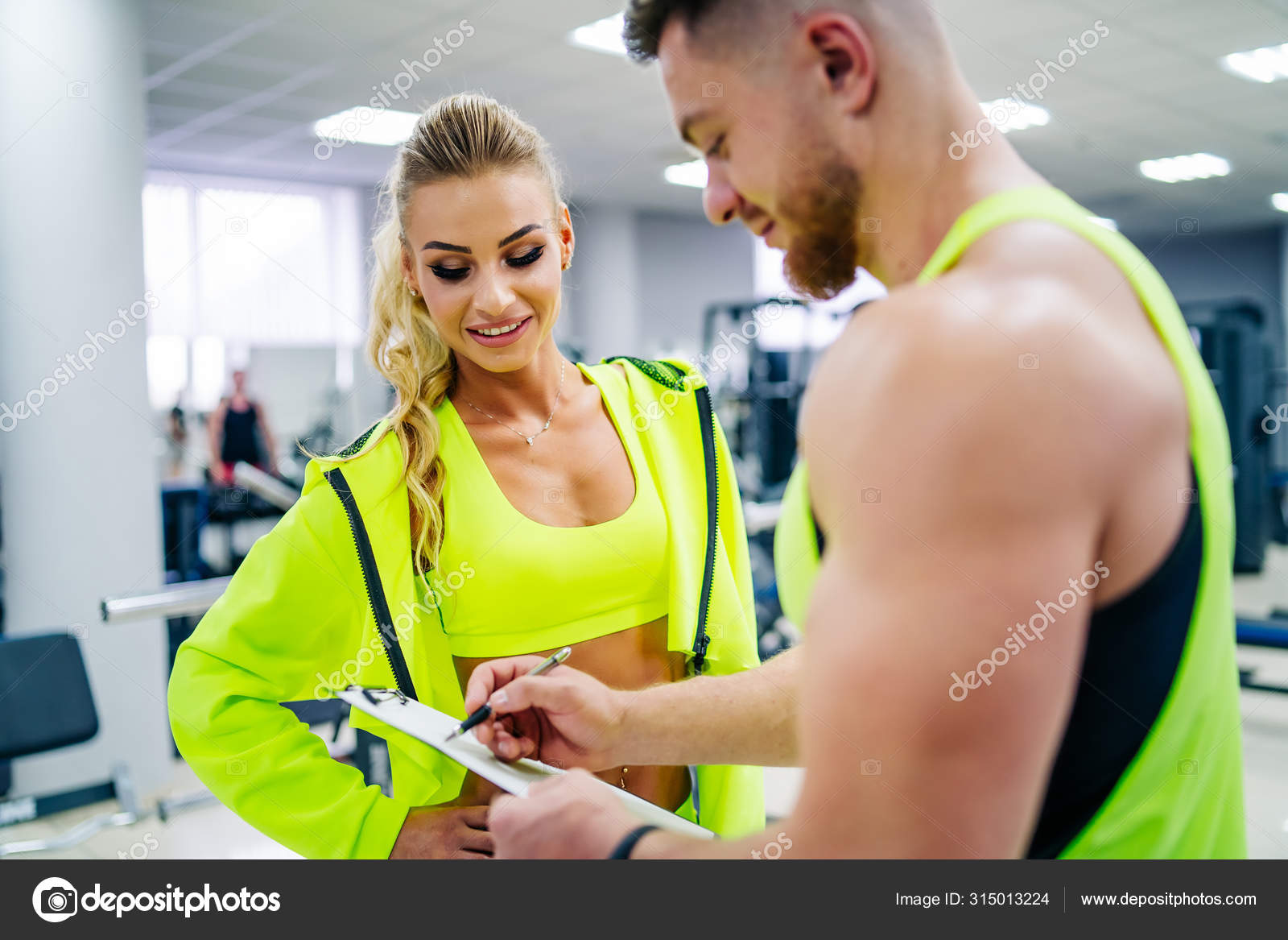 Personal trainer with a folder working with client woman at a gym ...