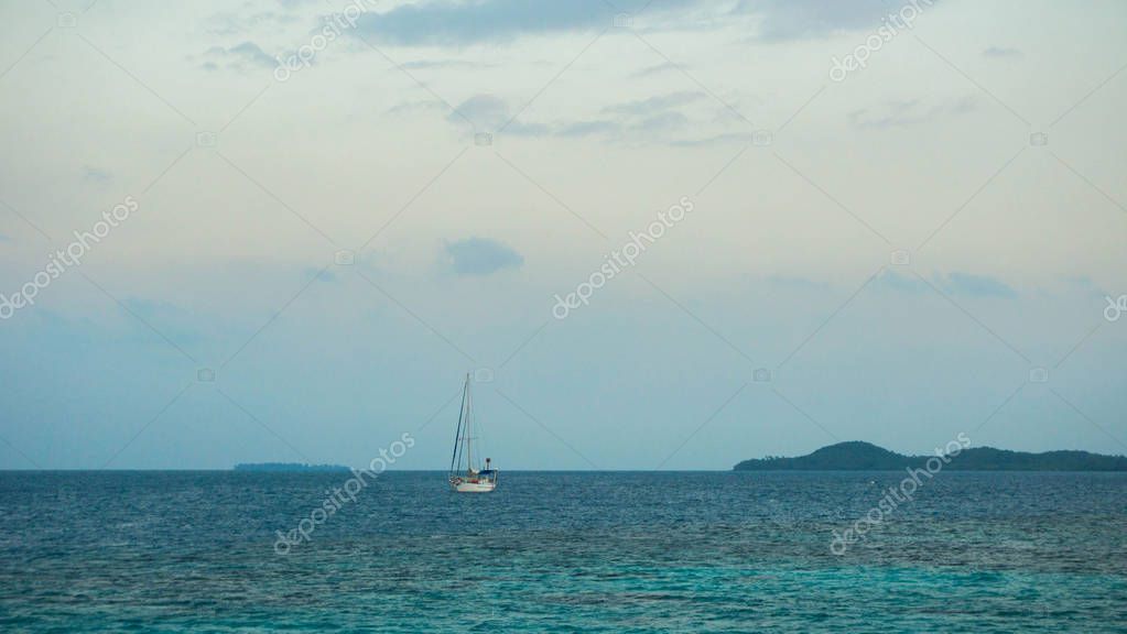 un yate pequeño del barco que navega en el medio del mar con la isla ...
