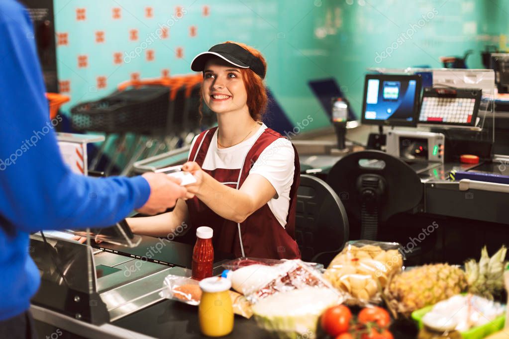 Hermosa cajera femenina sonriente en uniforme felizmente mirando al ...
