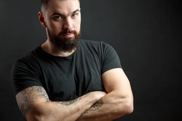 Strong man in black tight fitted shirt with a serious expression on his ...