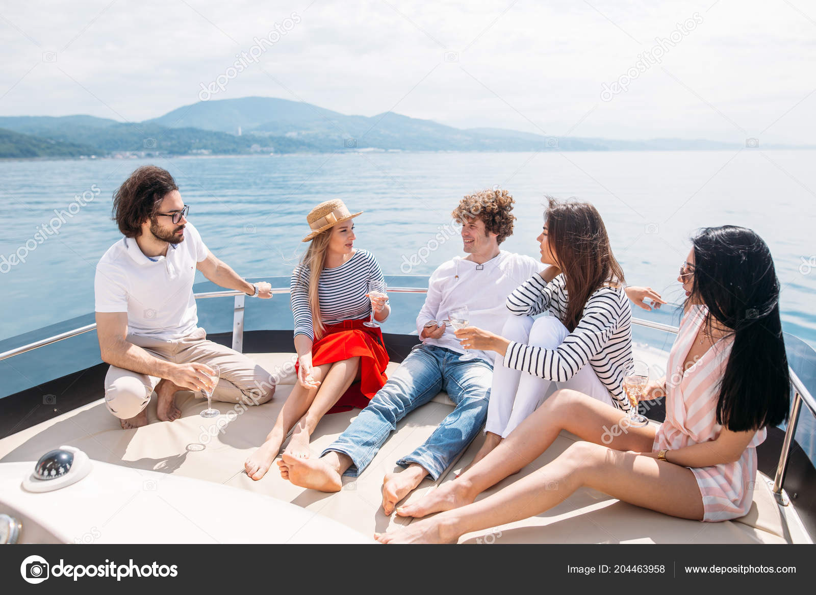 Friends having fun sailing on a yacht in sea, laughing, chatting and ...