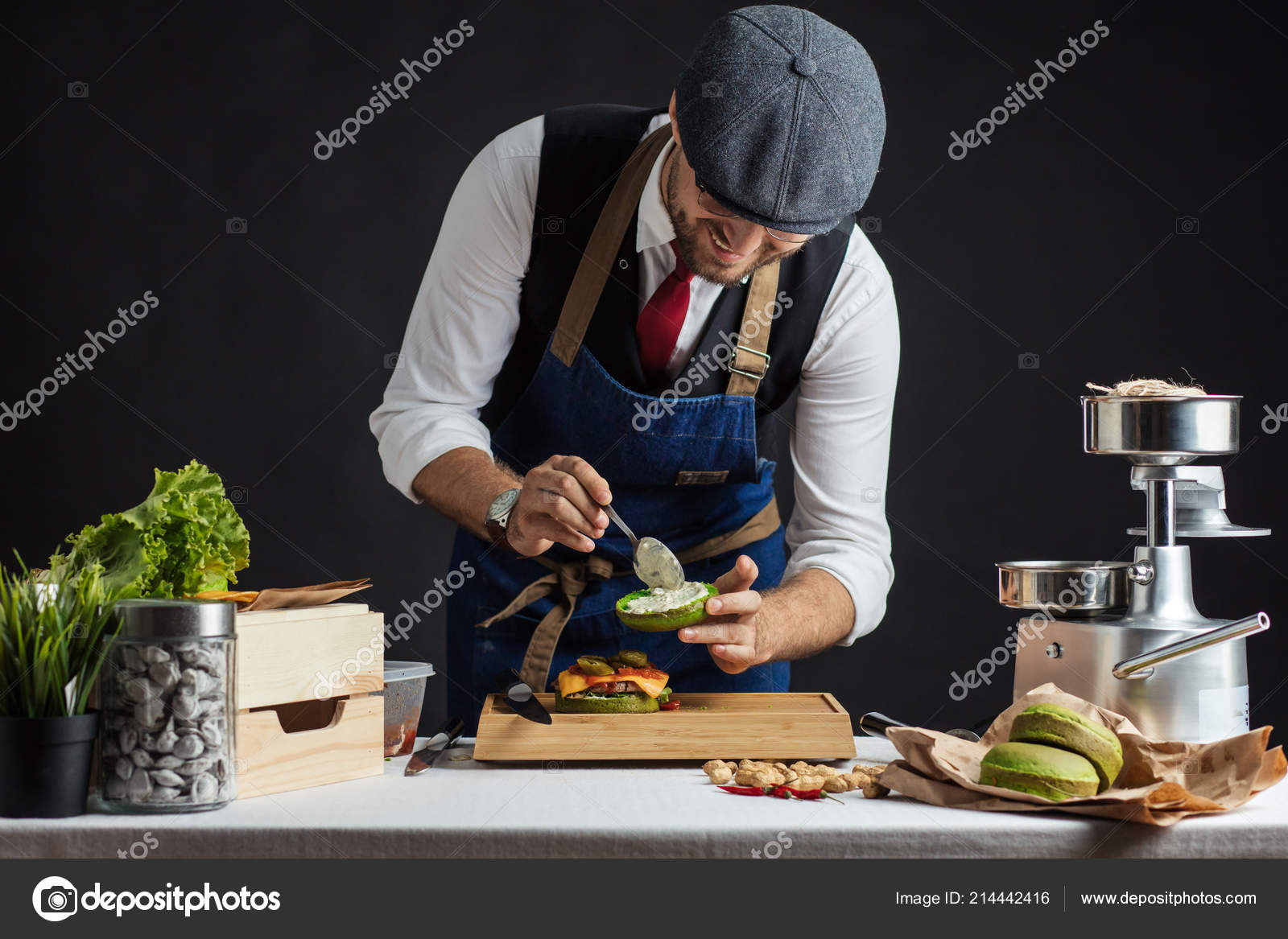 Cook preparing burger adding the sauce on green bun. Stock Photo by ...
