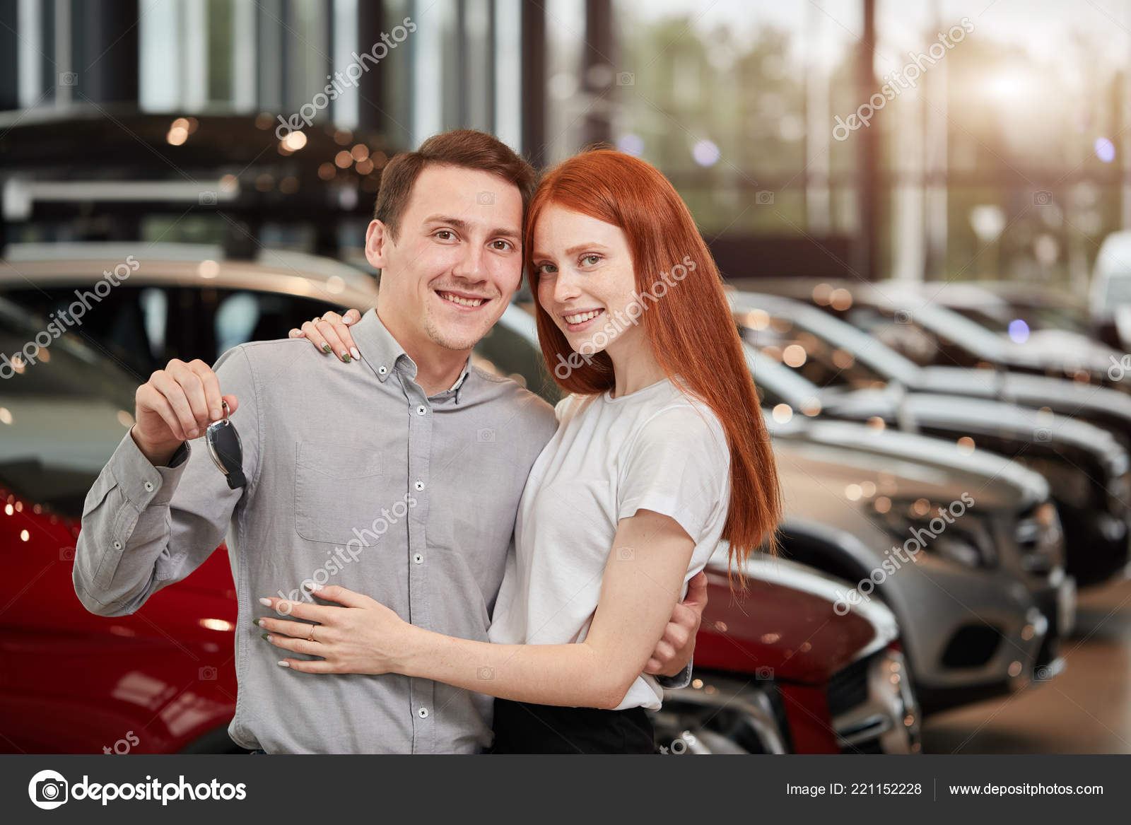 Beautiful couple is holding key of their new car, looking at camera and ...