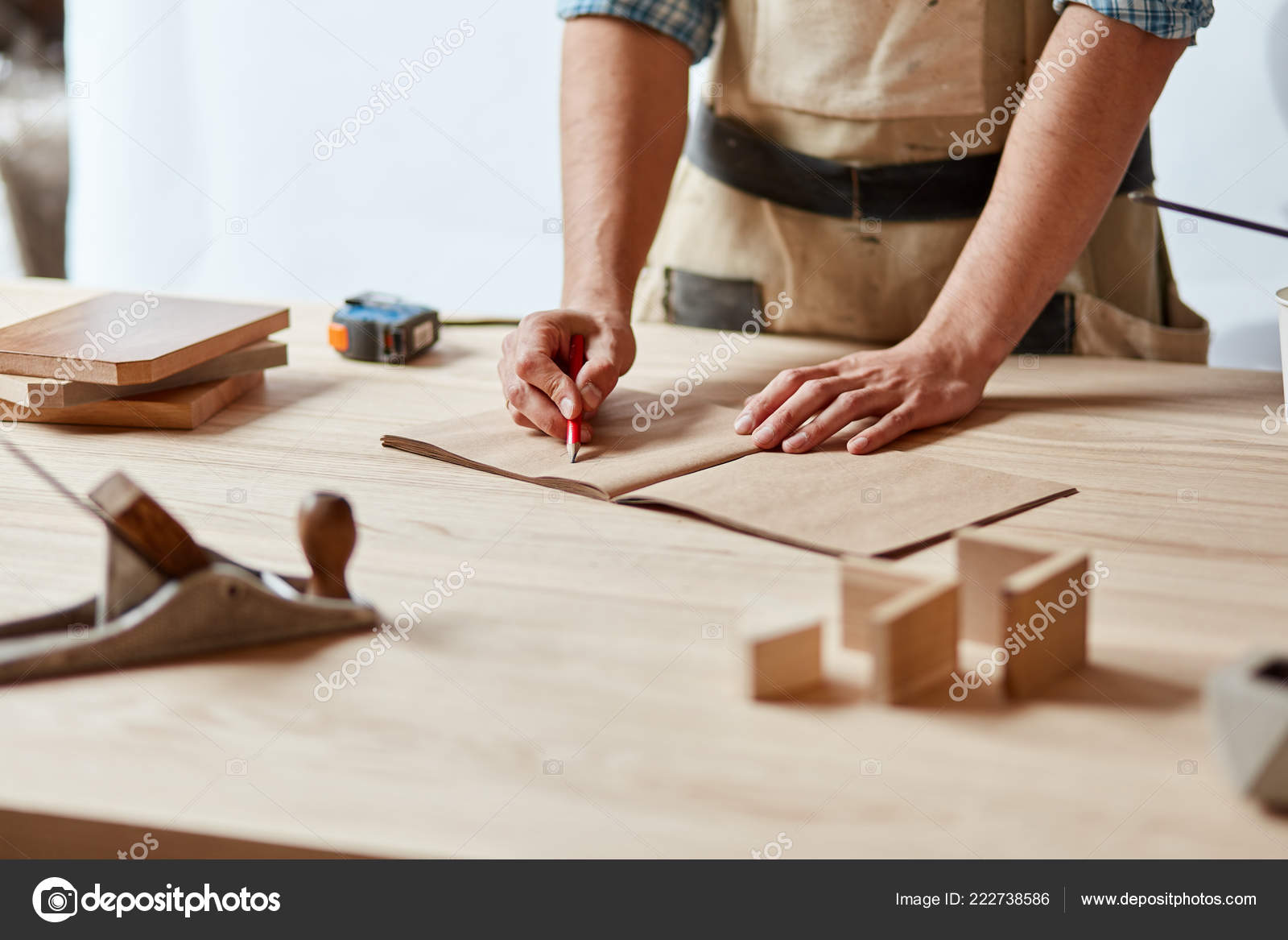 Closeup view of a carpenter using a red pencil to draw a line on a ...