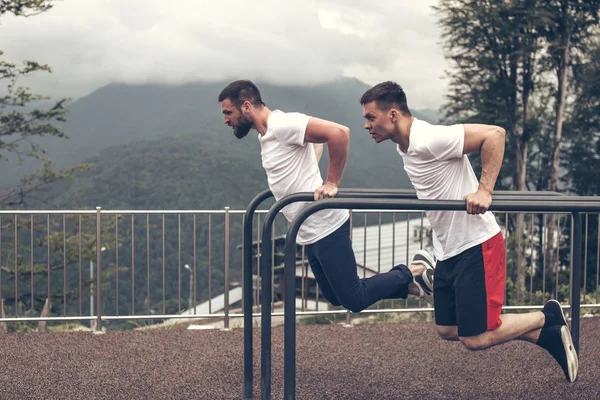 Two sportsmen doing dips on parallel bars - Stock Image - Everypixel