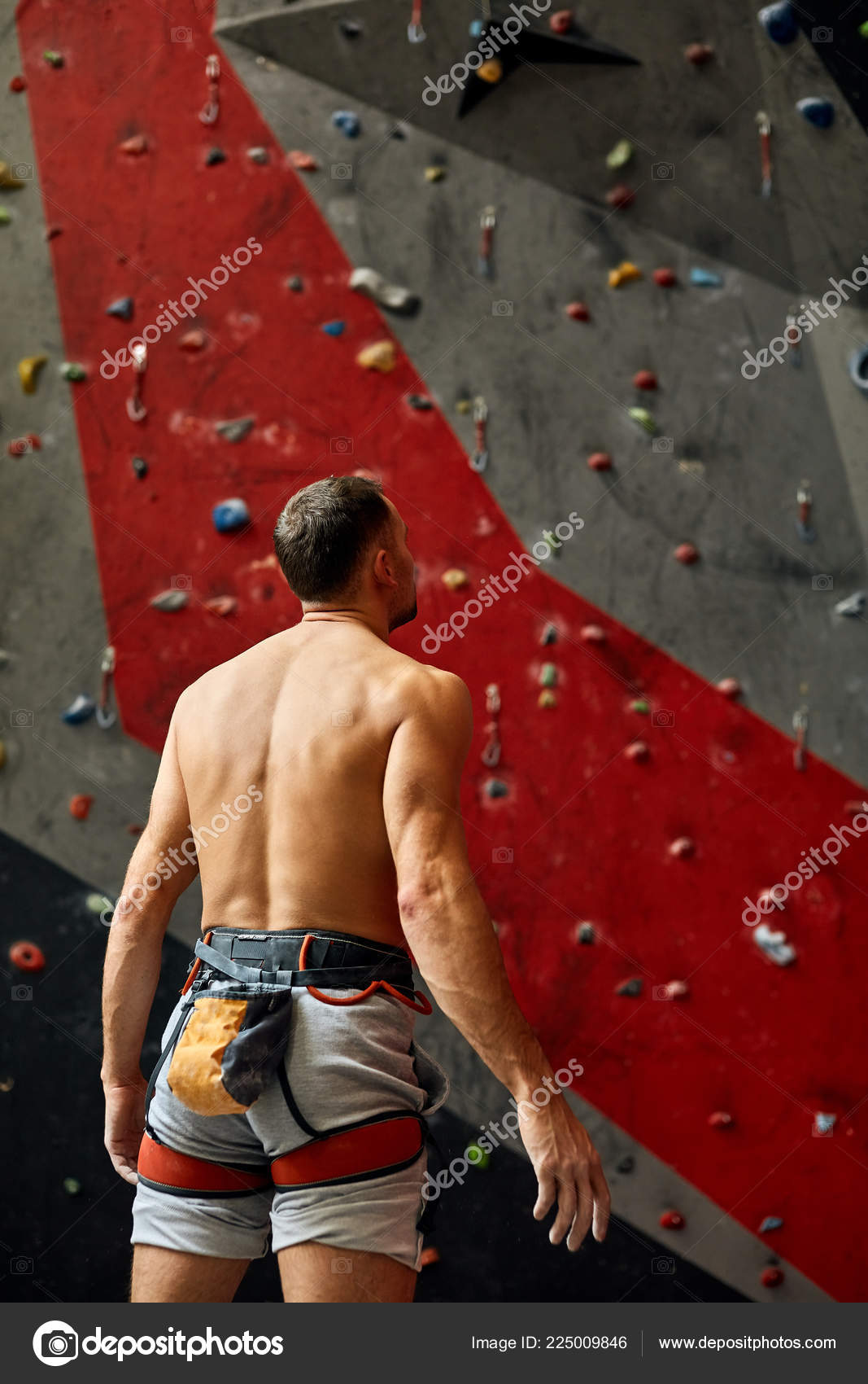 Back side of athlete man standing next to wall, ready for rock climbing ...