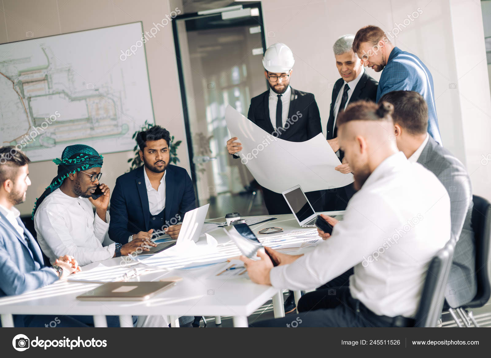 Multiracial group of constructors and architects discussing blueprint ...