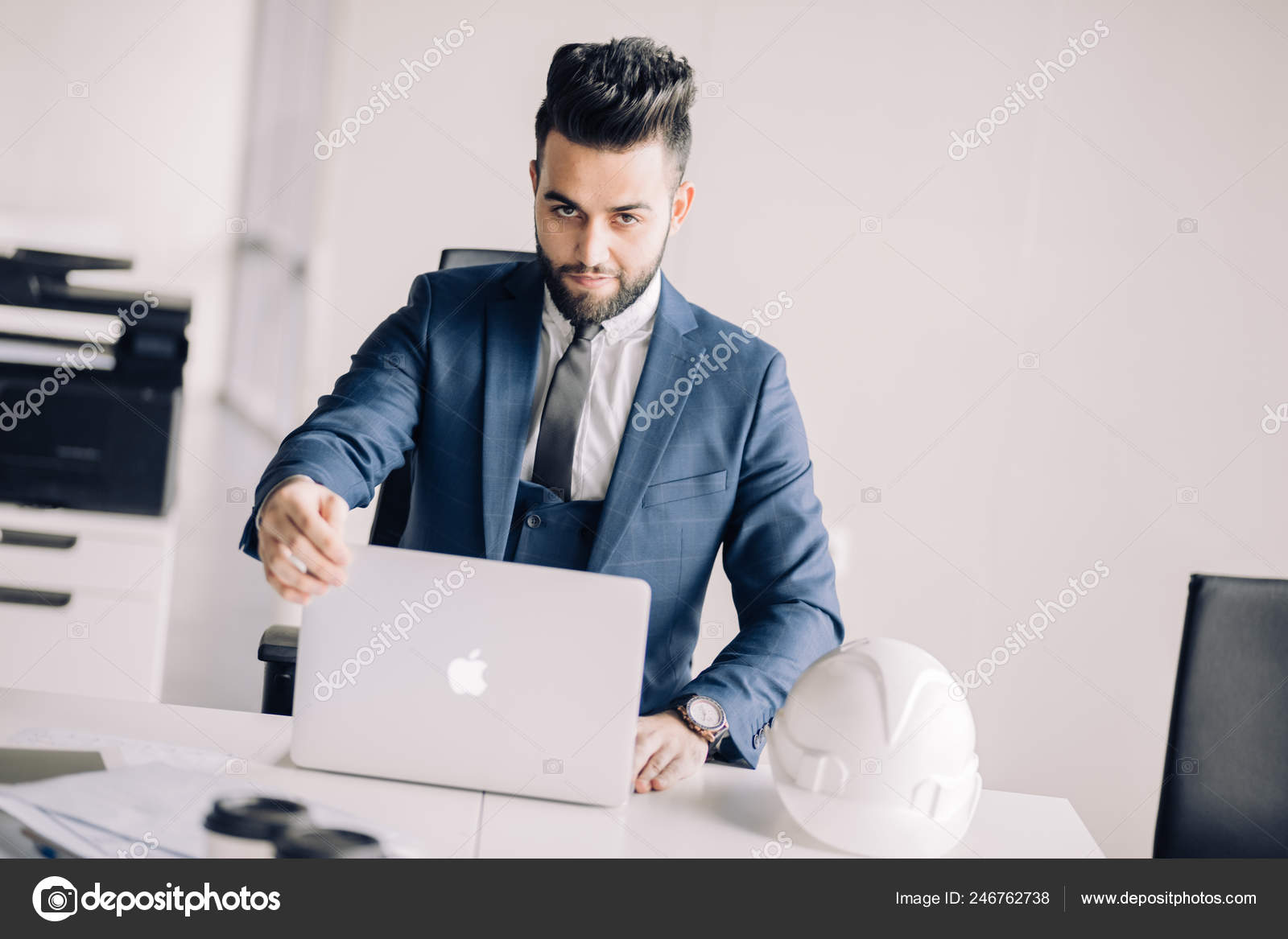 Officer 30s in formal suit sitting alone in well-lit office, working on ...