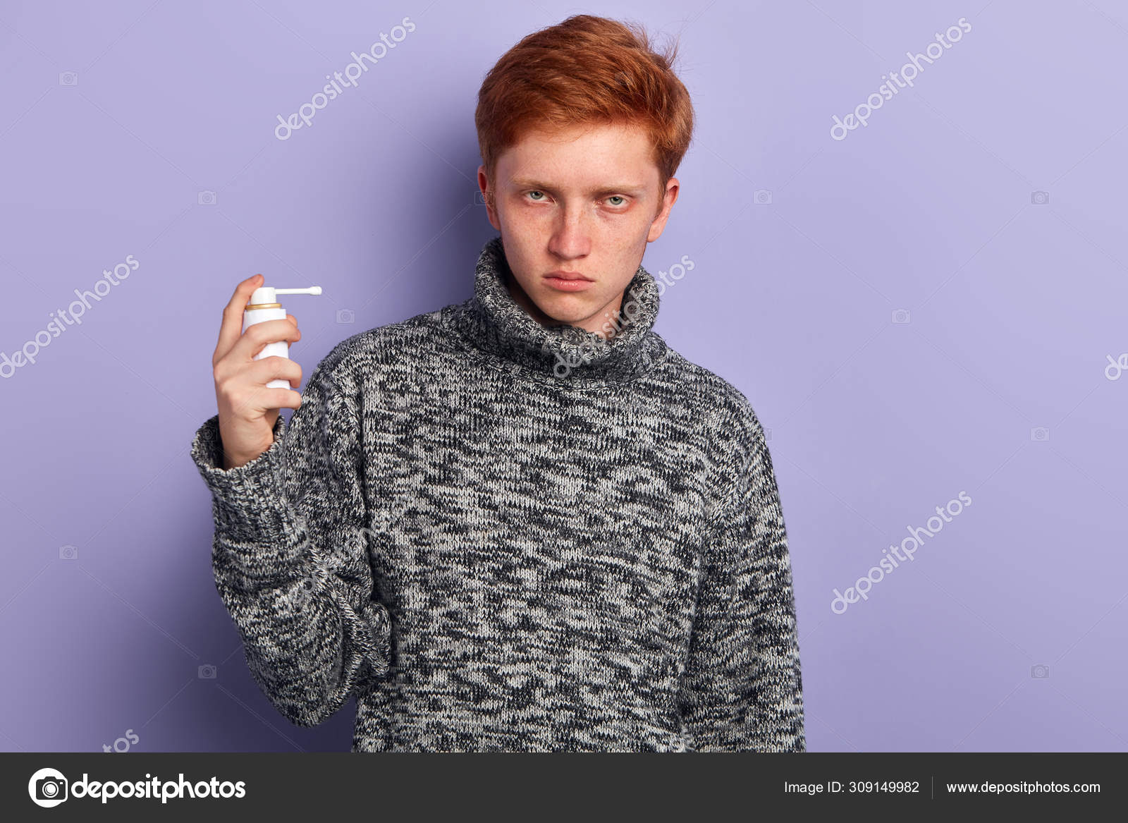 A sick poor man holding a nasal spray in his hand on blue background ...