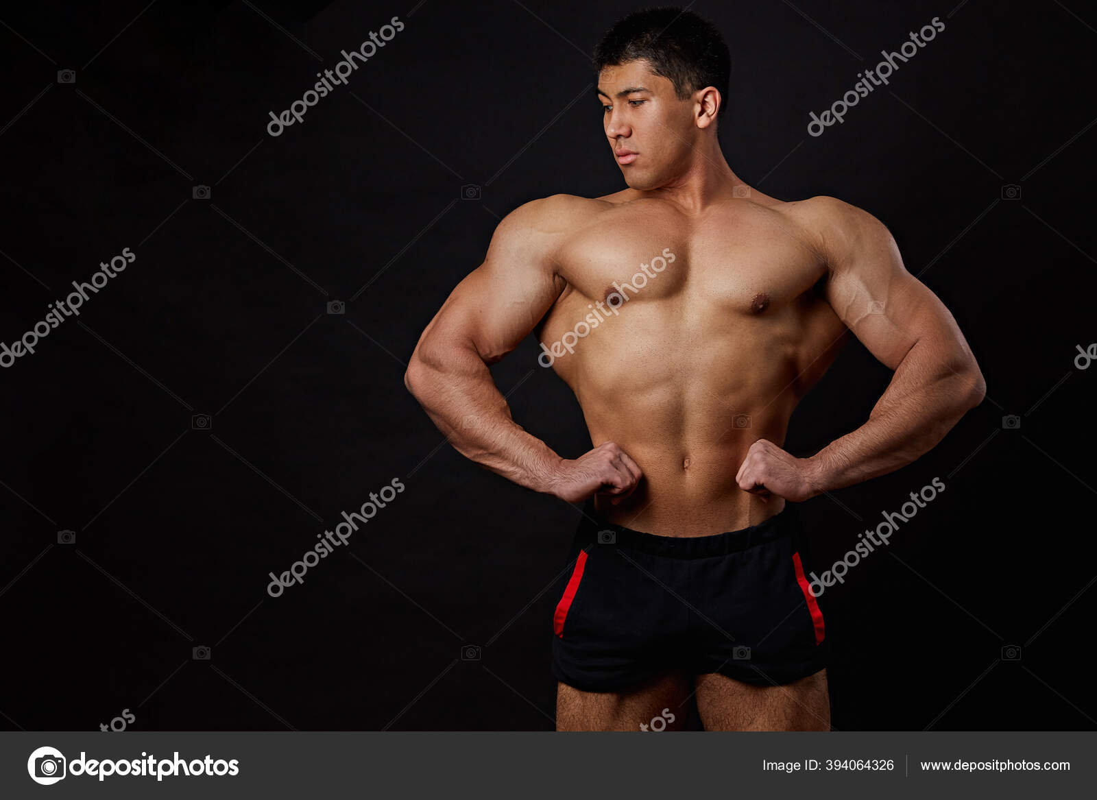 Serious well-built guy holding his hands on the hips and looking aside ...