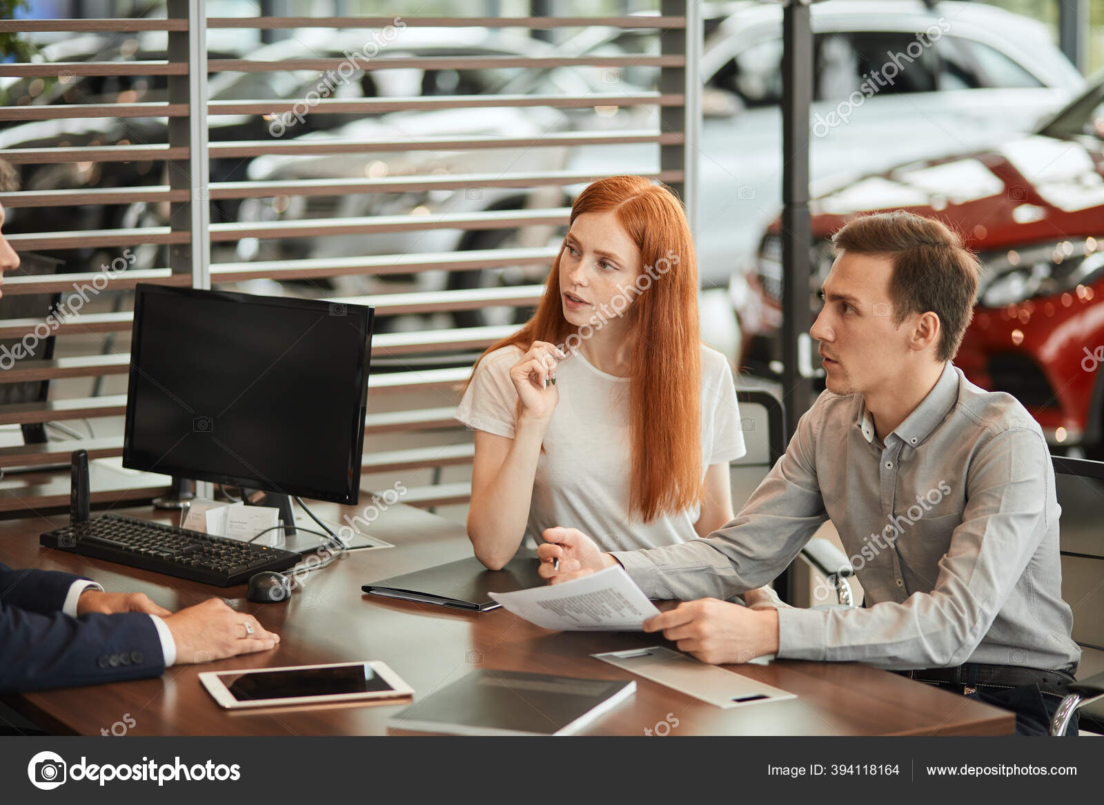 Beautiful young couple signs documents at dealership showroom. Stock ...