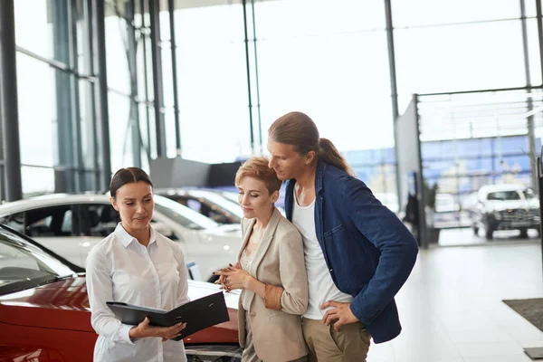 Car sales manager telling about the features of the car to the ...