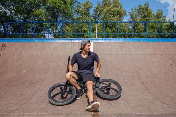 Rider sitting on BMX in skate park resting after riding — Stock Photo ...