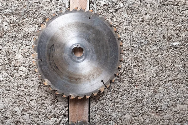 the disc of a circular saw hanging on a nail on the concrete wall of ...
