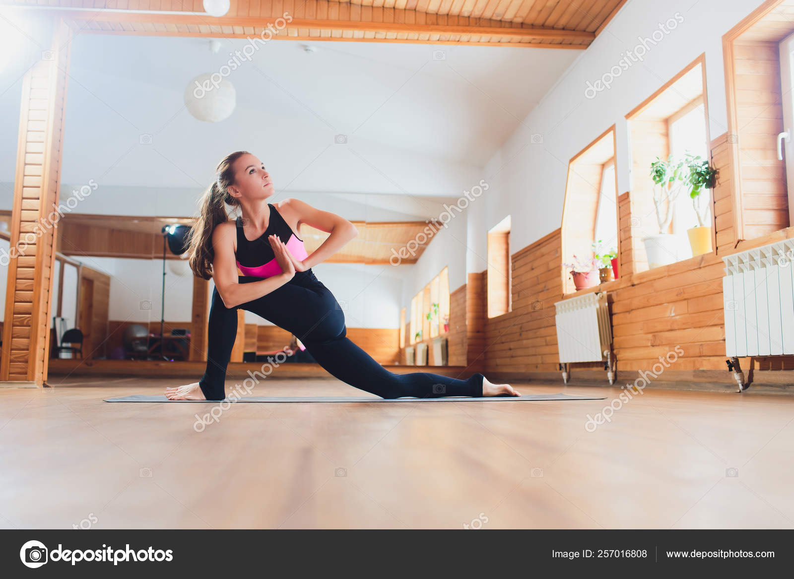 Young attractive yogi woman practicing yoga, standing in Parivrtta ...