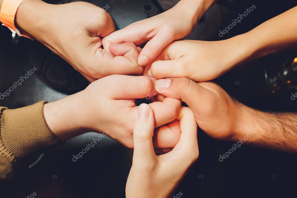 dos hombres y tres mujeres tomados de la mano en una mesa que implica ...