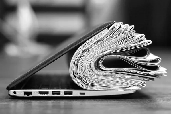 Open laptop and stack of newspapers. Daily journals with news and ...