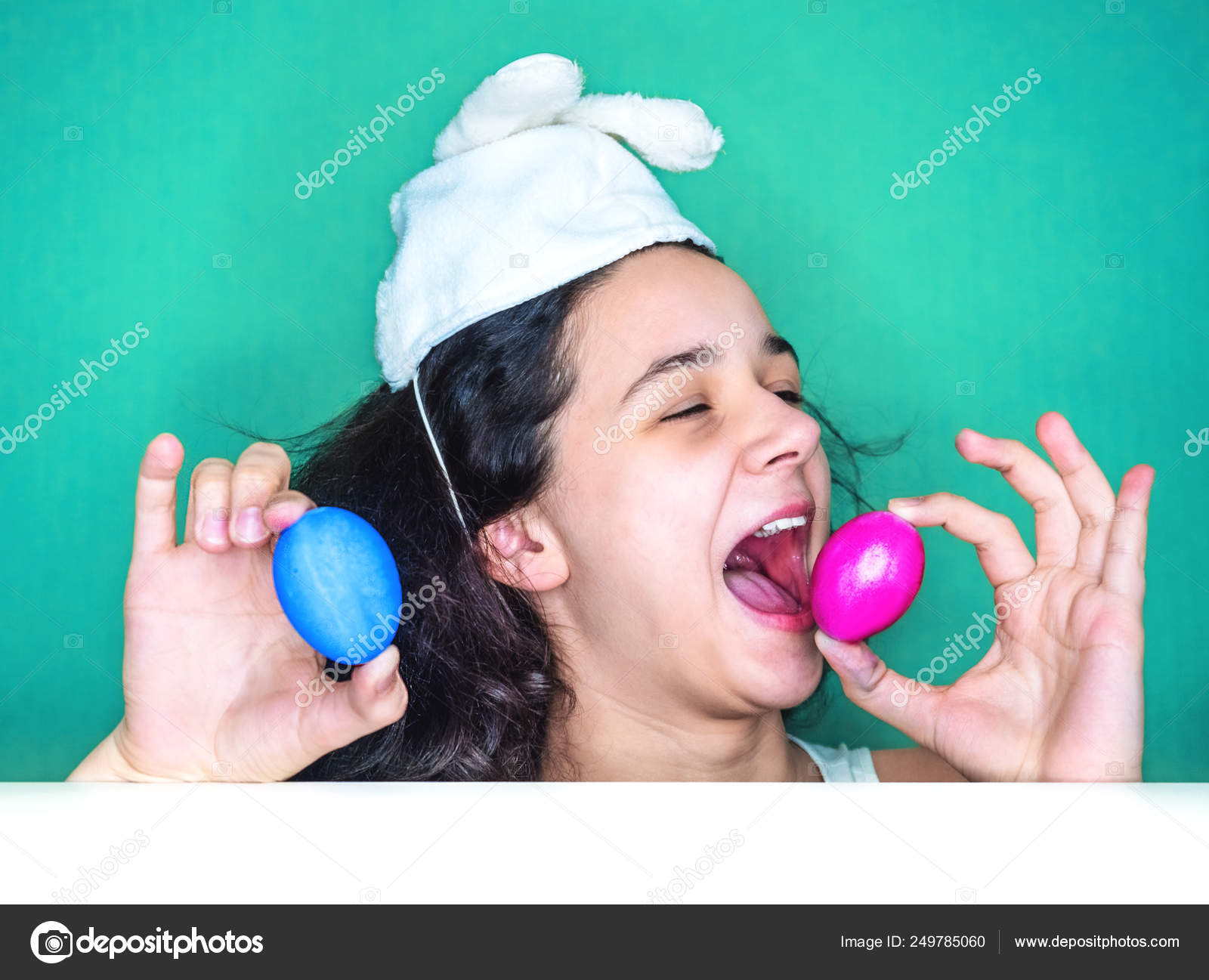 Woman holding egg. Young brunette woman wearing easter bunny ears ...