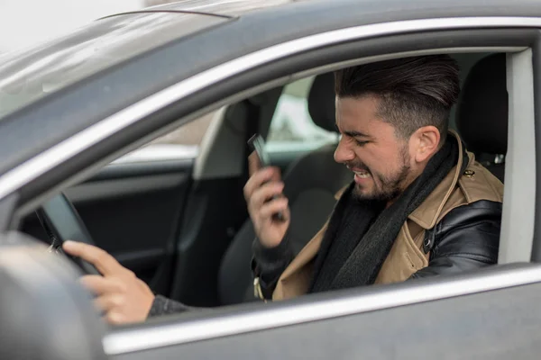 Handsome young man fighting on the phone while driving his car daytime ...
