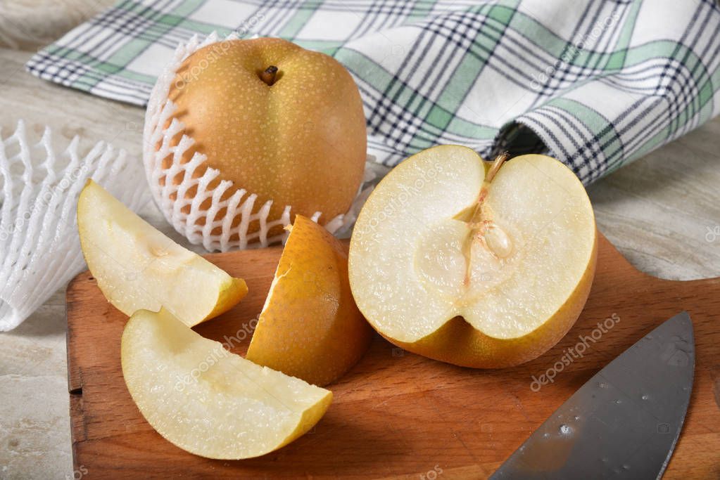Las peras asiáticas cortadas en rodajas en una tabla de cortar. También ...