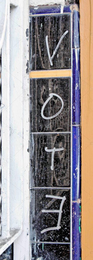 Crudamente escrito VOTE graffiti en la pared con la letra "E" al revés ...