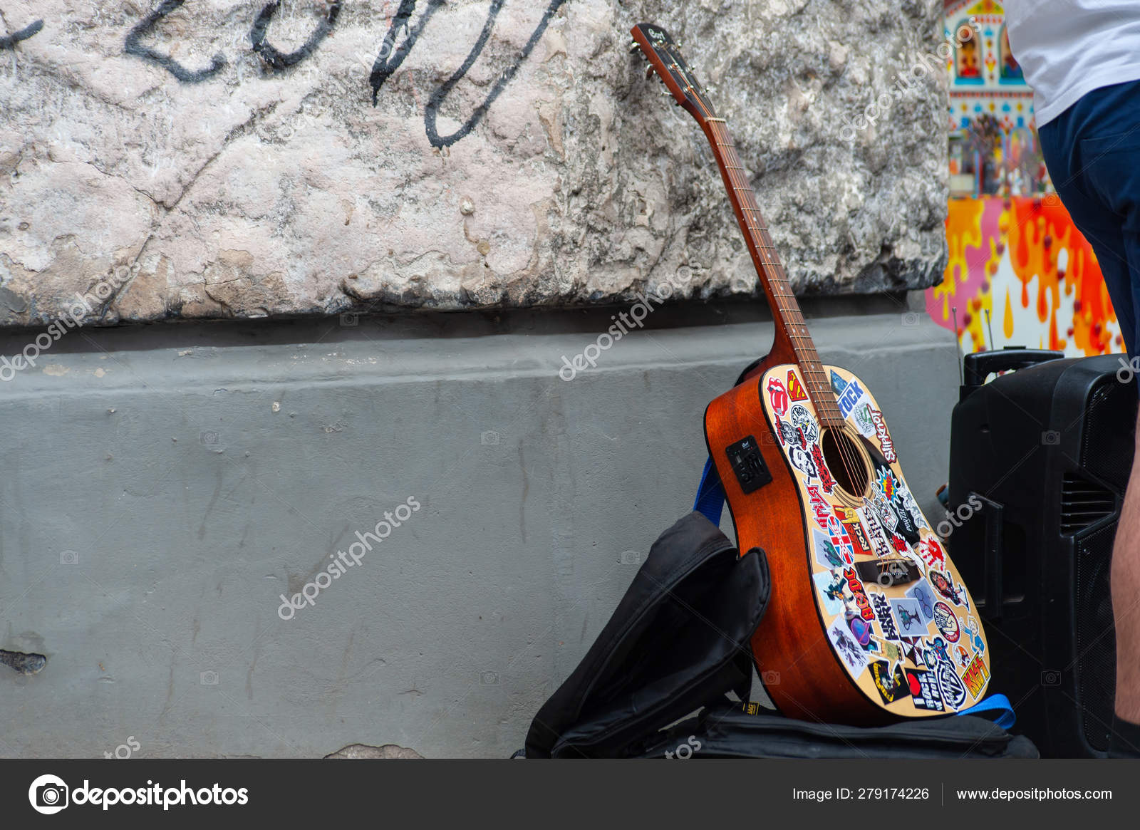 Acoustic guitar with rock band labels stickers stays on the stre ...