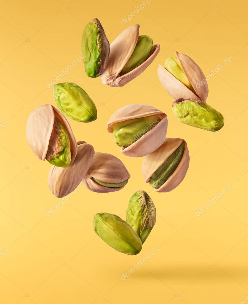 Volando en aire fresco crudo entero y pistachos agrietados aislados ...