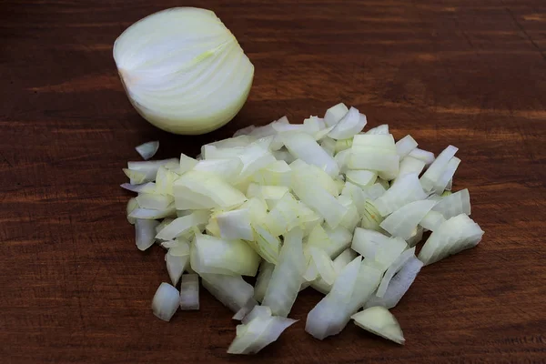 White onion, cut into small pieces on a wooden background next to a ...