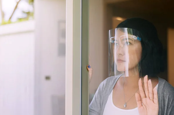 Asian woman wearing face shield with hands touching on window,Stay at ...