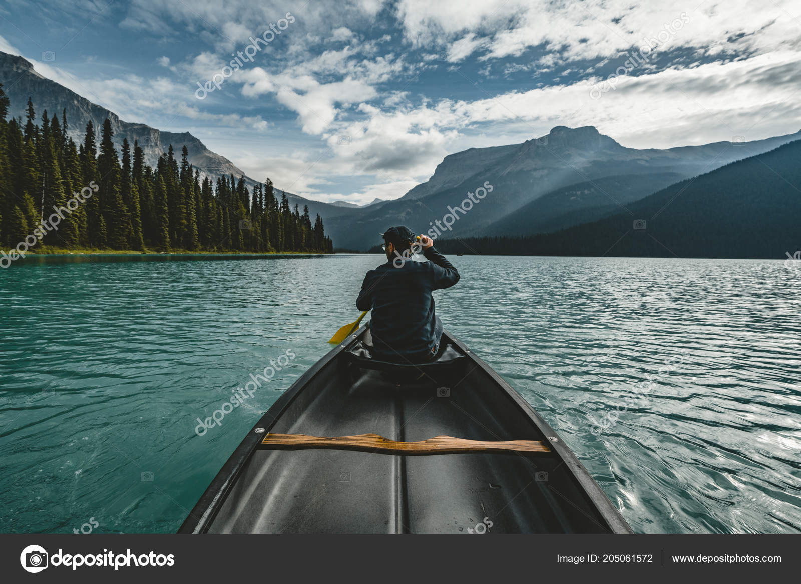 Young Man Canoeing on Emerald Lake in the rocky mountains canada with ...