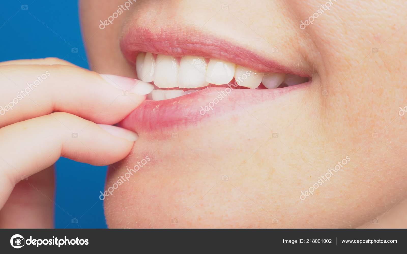 Closeup, female lips without makeup, girl chewing nails, on a blue ...