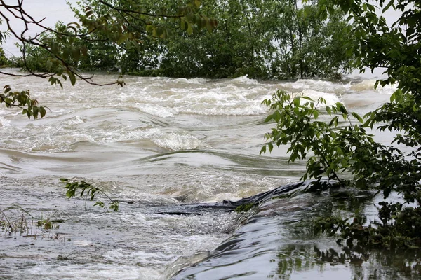 Fast flowing muddy flood water going over temporary sandbags flood ...