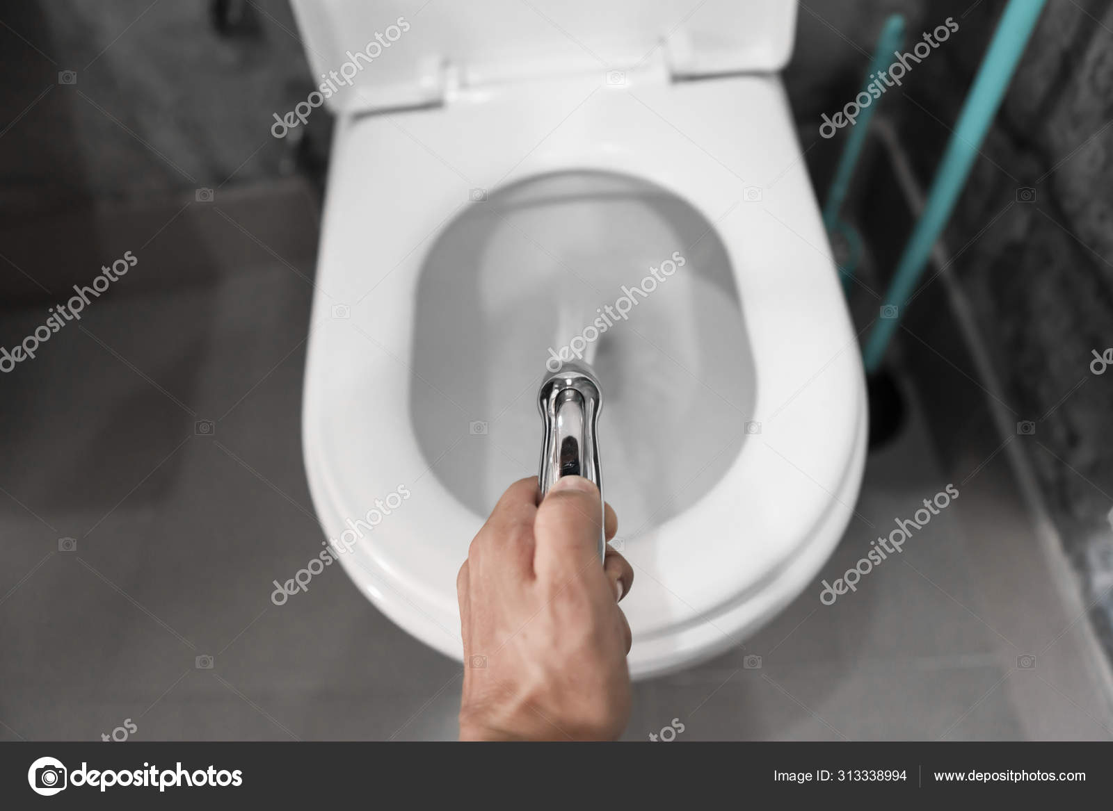 Using of bidet shower with a white toilet. Bidet shower in male hand ...