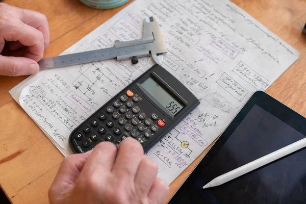 old man doing some math calculations using digital calculator at his ...