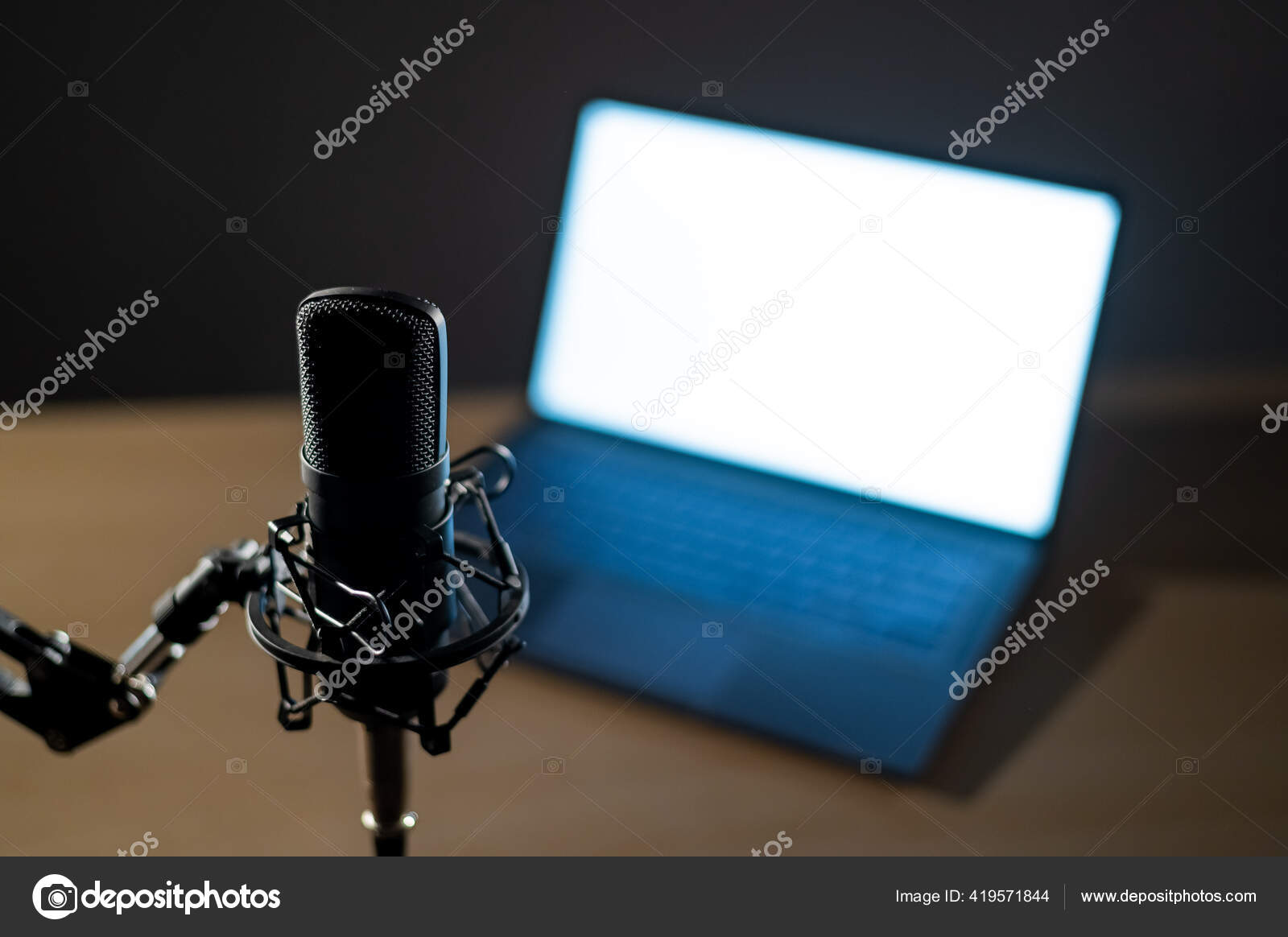 Professional microphone and laptop with white screen in the dark ...