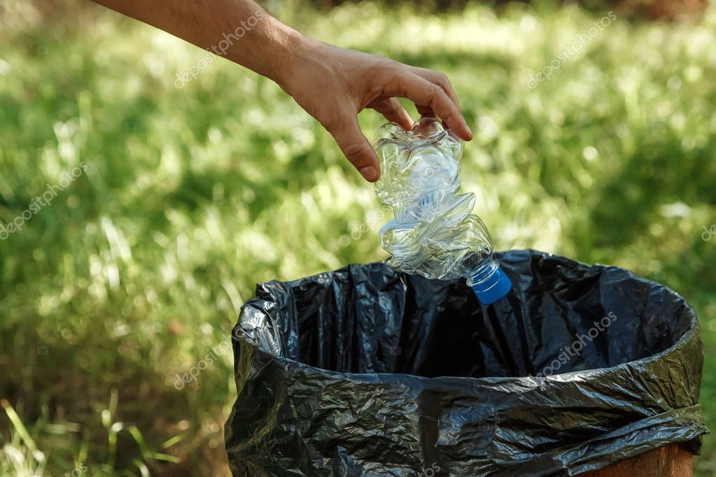 Close up Mano lanzando una botella de plástico vacía a la basura 2024