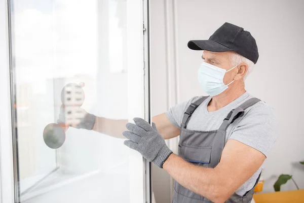 Worker man installs plastic windows and doors with double-glazed white ...