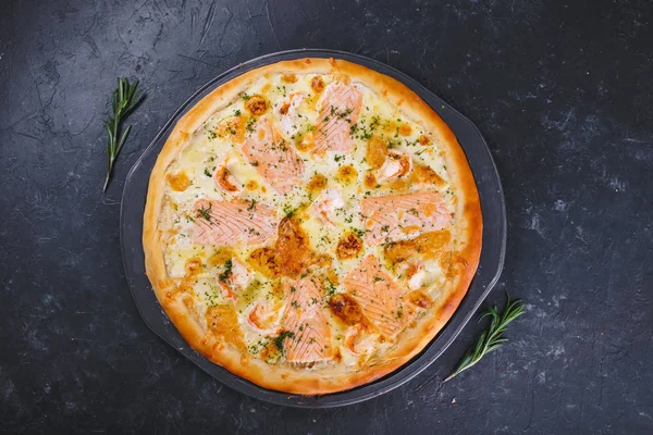 Pizza with cheese shrimp and fish and mozzarella on a dark background ...