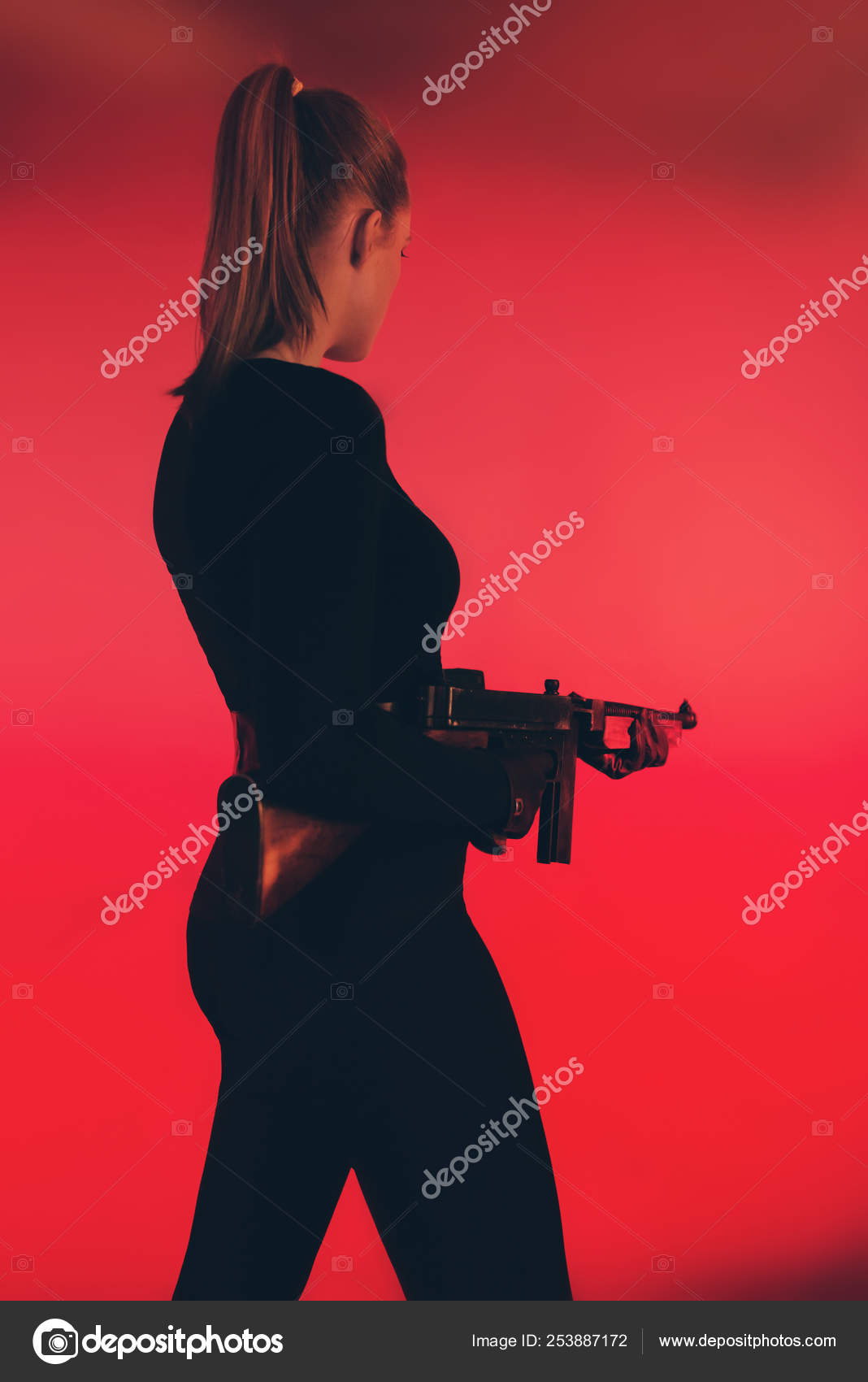Young woman standing with machine gun against red background. Stock ...