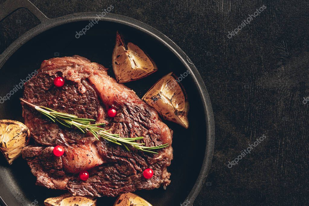 vista superior del filete cocido con romero, limones y bayas en la ...