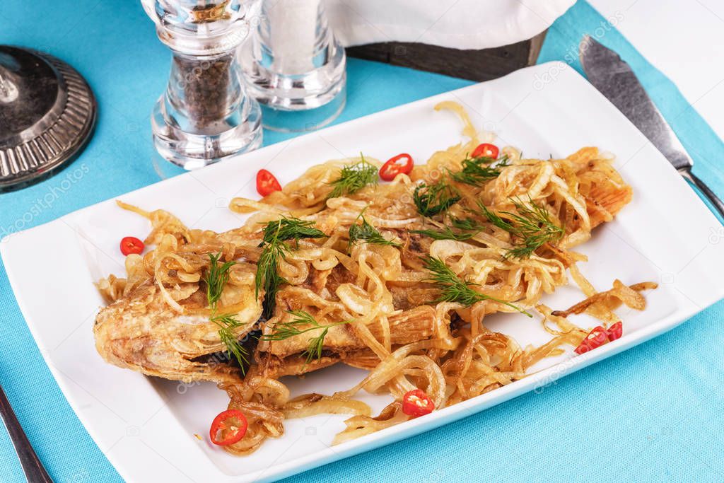 La carpa de pescado de río frito se sirve bajo los aros de cebolla ...